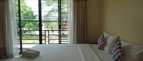 Quarto de hotel com uma cama grande, duas almofadas, uma janela com cortinas e um ar condicionado.