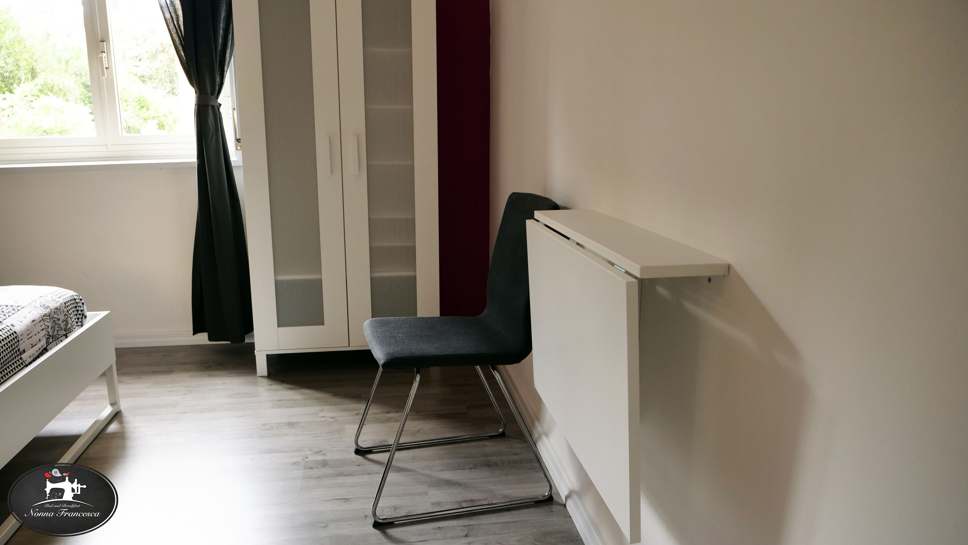 Um quarto com cama, uma cadeira, radiador e janela com cortinas.
