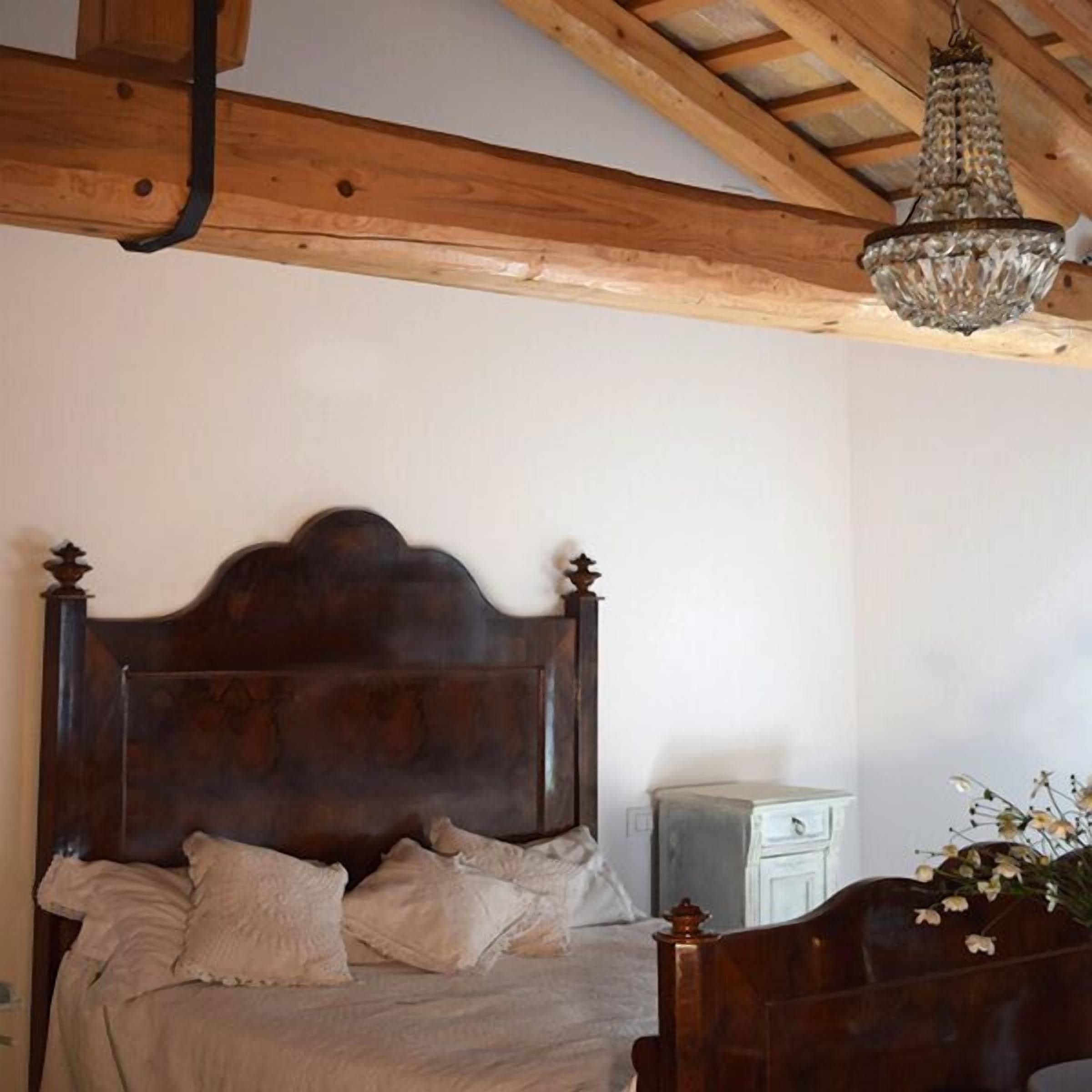 Quarto com cama de madeira, mesa de cabeceira e um candelabro.