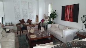 Sala de estar com sofá, poltronas, mesa de centro e objetos decorativos.