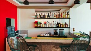 Uma área de bar com duas cadeiras verdes, um balcão com uma máquina de café e prateleiras cheias de garrafas de bebidas.