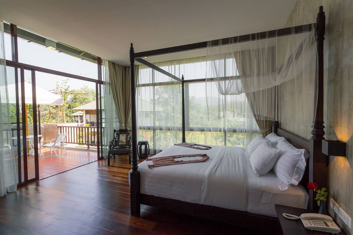 Quarto espaçoso com cama grande, varanda com mobiliário de exterior e vista para o exterior.