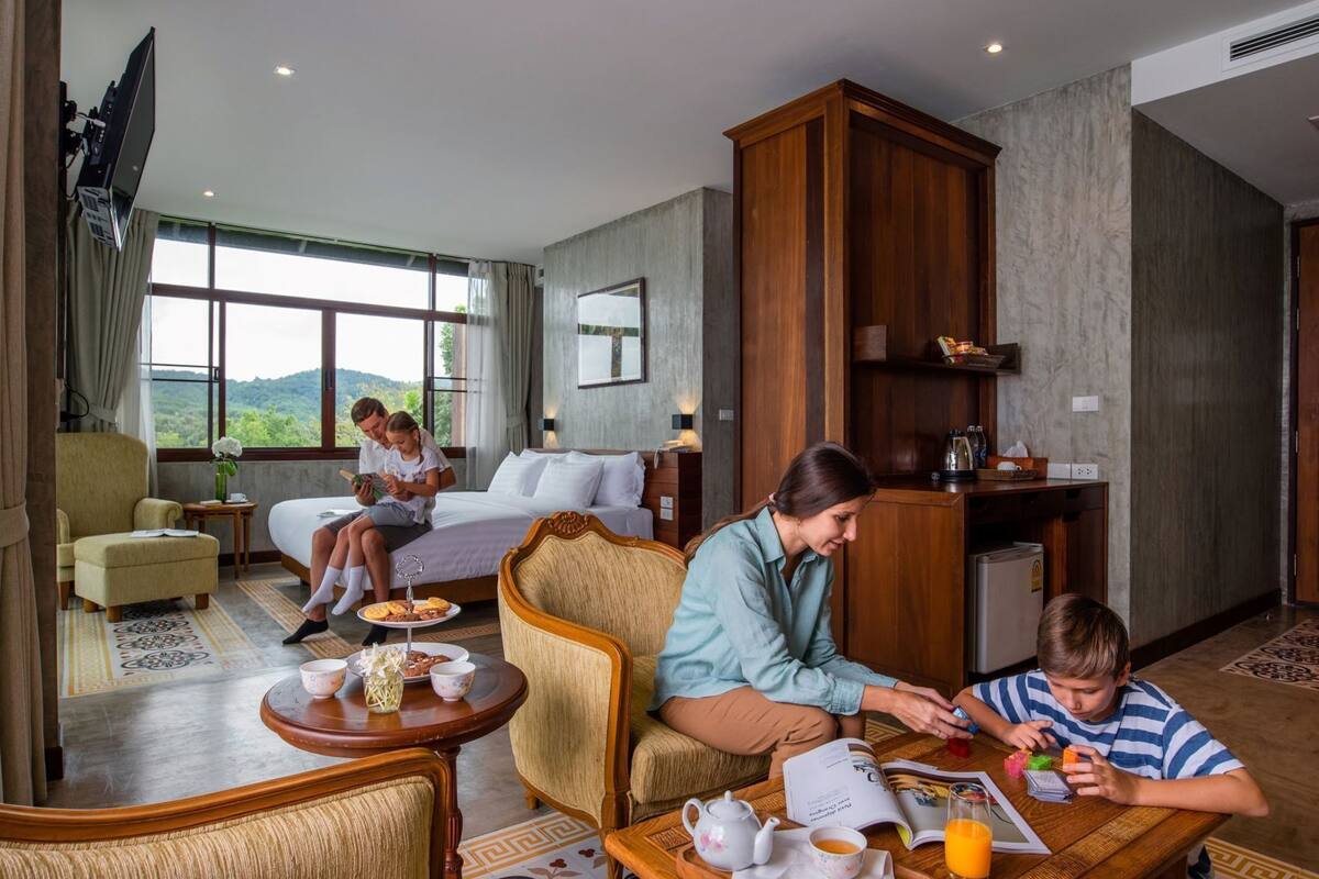 Quarto de hotel com cama, mesa de jantar com café da manhã, televisão e vista para o exterior.