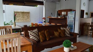 Uma sala de estar acolhedora com um sofá de madeira, cadeiras e uma mesa de centro.