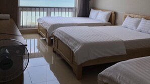 Quarto de hotel com duas camas, uma escrivaninha e vista para o oceano.