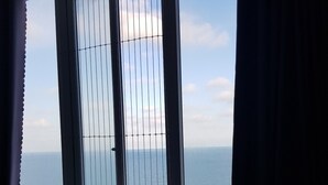 Quarto com uma grande janela com vista para a praia.