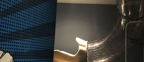 Um interior moderno com uma parede perfurada, estrutura metálica curva e luminária embutida no teto.