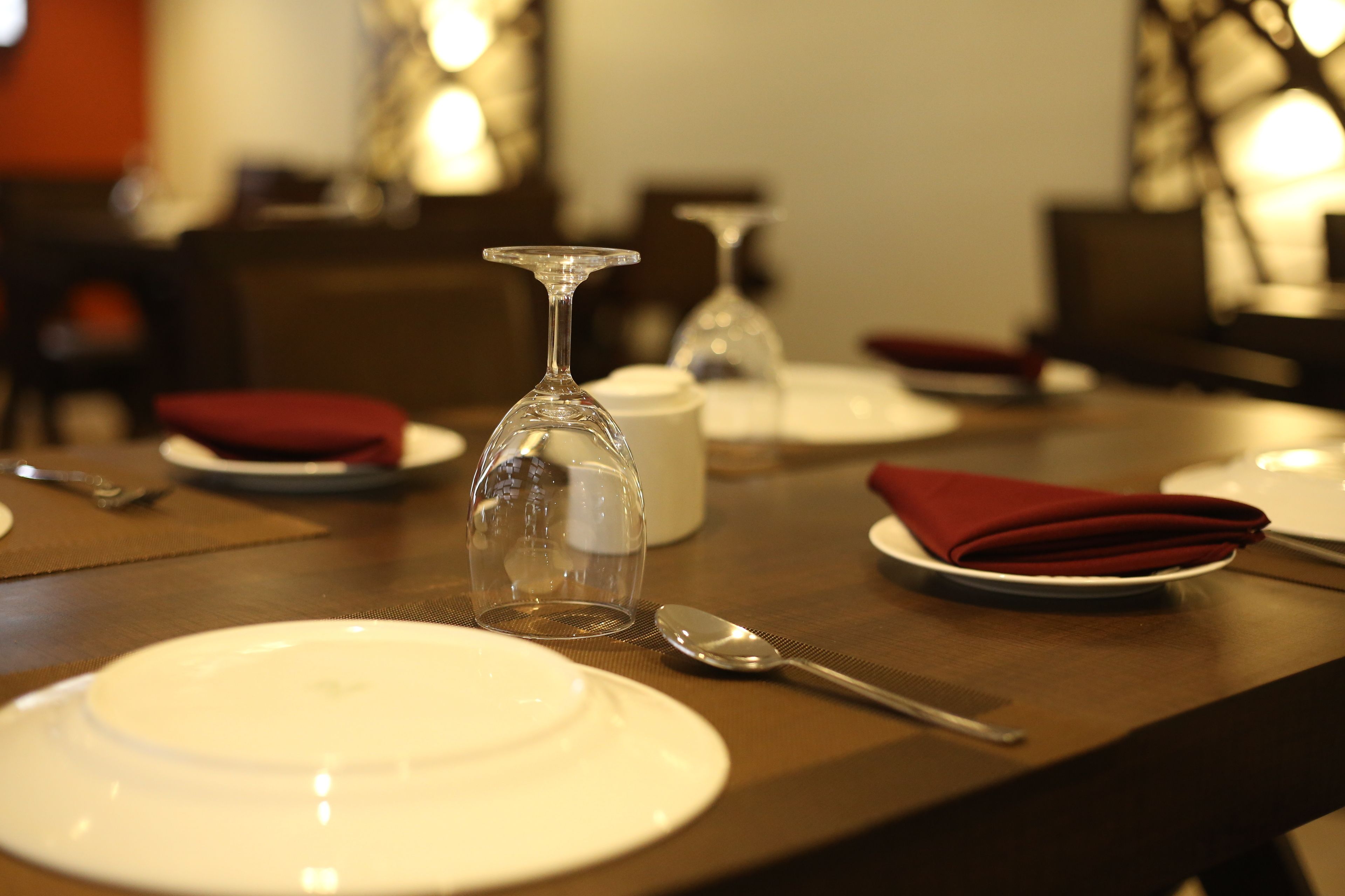 Uma mesa de jantar posta com pratos, uma taça de vinho, uma colher e um guardanapo.