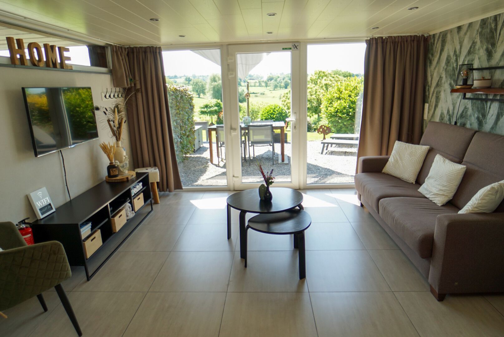 Uma sala de estar com sofá, mesa de centro, televisão e uma porta de vidro deslizante que dá para uma área externa.