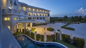 Um hotel moderno com piscina, várias varandas e entrada bem iluminada.