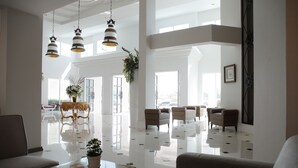Um quarto espaçoso e bem iluminado, com piso lustroso, móveis elegantes e grandes janelas que permitem a entrada de luz natural.