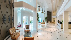 Um hall amplo com piso de mármore, mobiliário elegante e um lustre moderno.