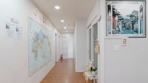 Um corredor com piso de madeira, um grande mapa-múndi e uma pintura em estilo asiático tradicional.