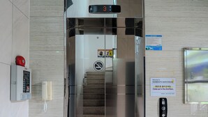 Um elevador com visor digital, placa de proibido fumar e indicação para a Rainbows Guesthouse.