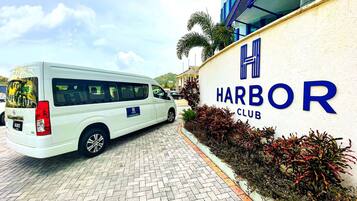 Uma carrinha branca estacionada em frente a um edifício com uma placa que diz 'HARBOR CLUB'.