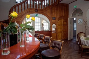 Um interior de madeira com uma mesa curva, cadeiras e vasos com flores.