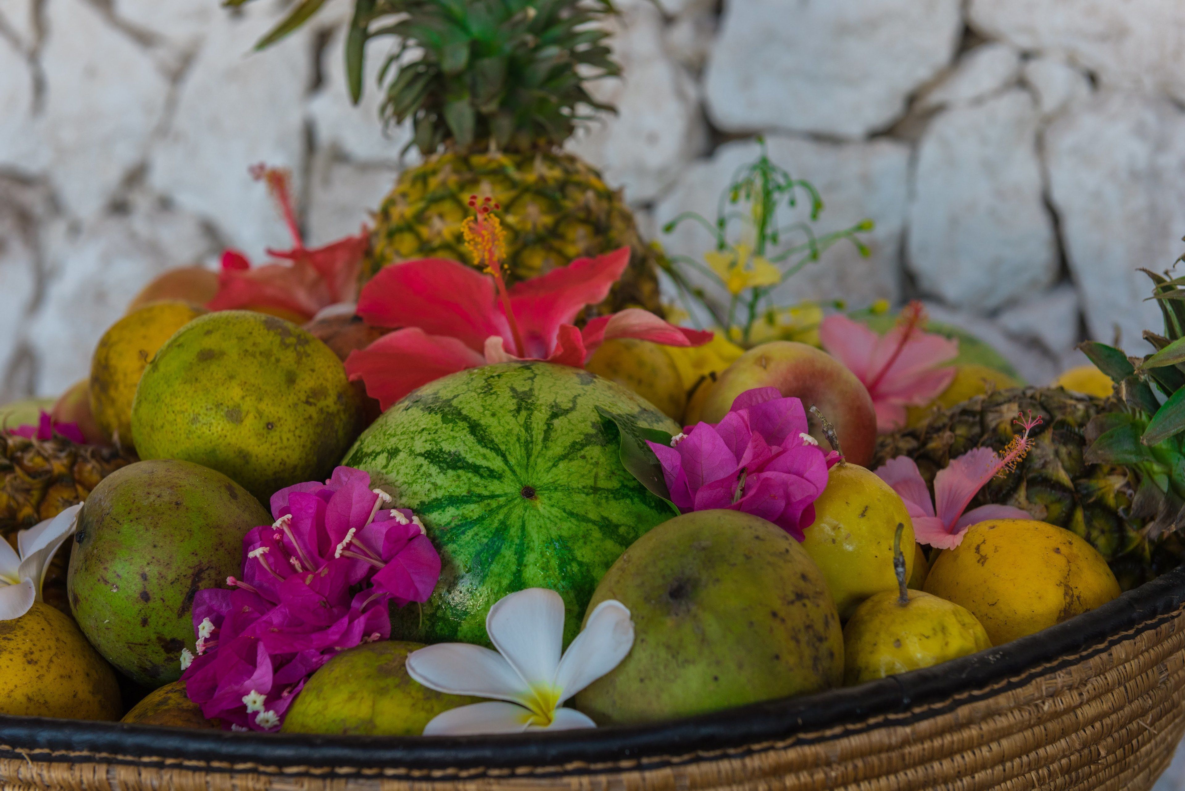 Uma cesta com frutas e flores diversas.