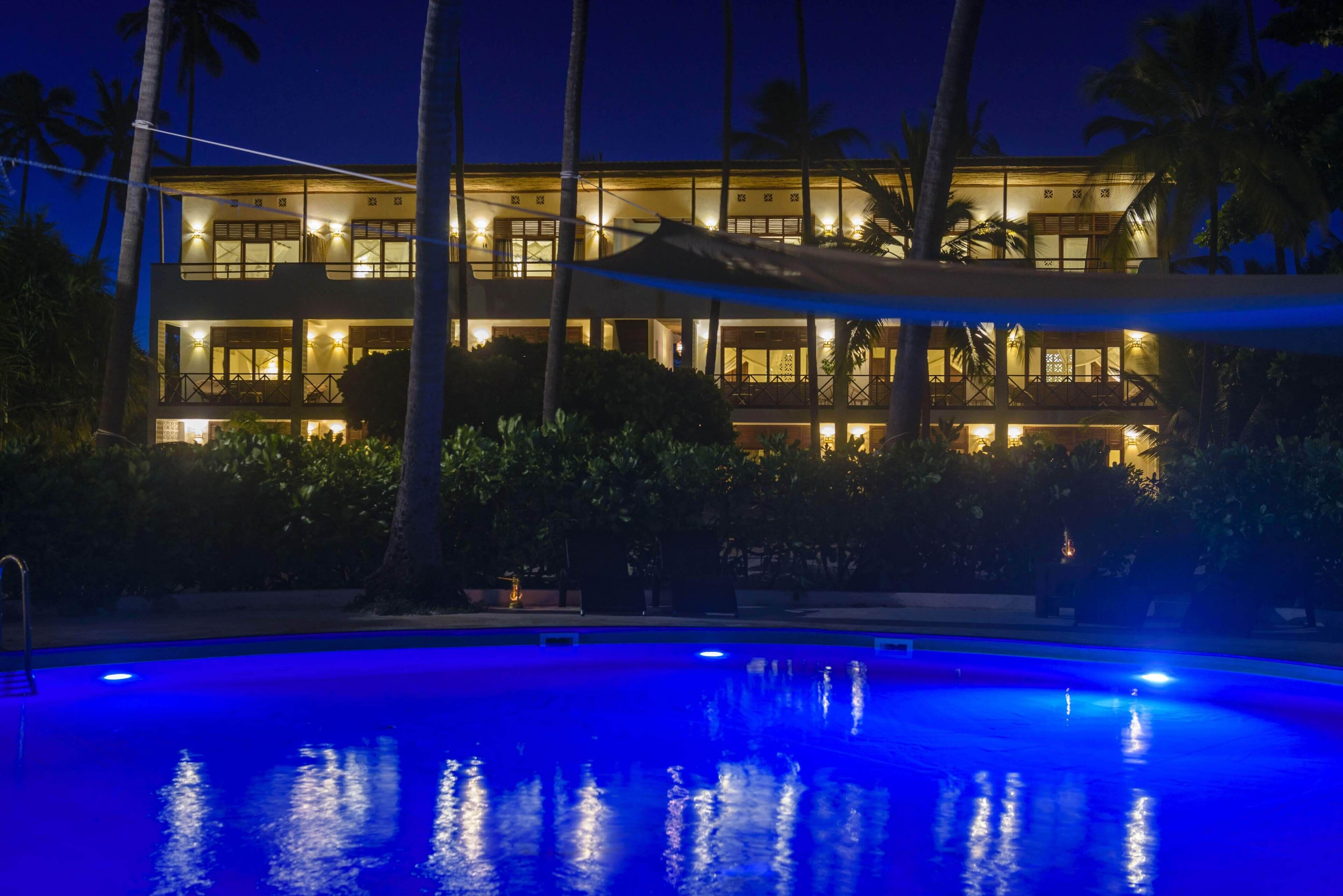 Um hotel de dois andares com piscina à noite.