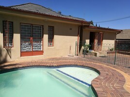 Uma casa com piscina, quintal cercado e porta de entrada.