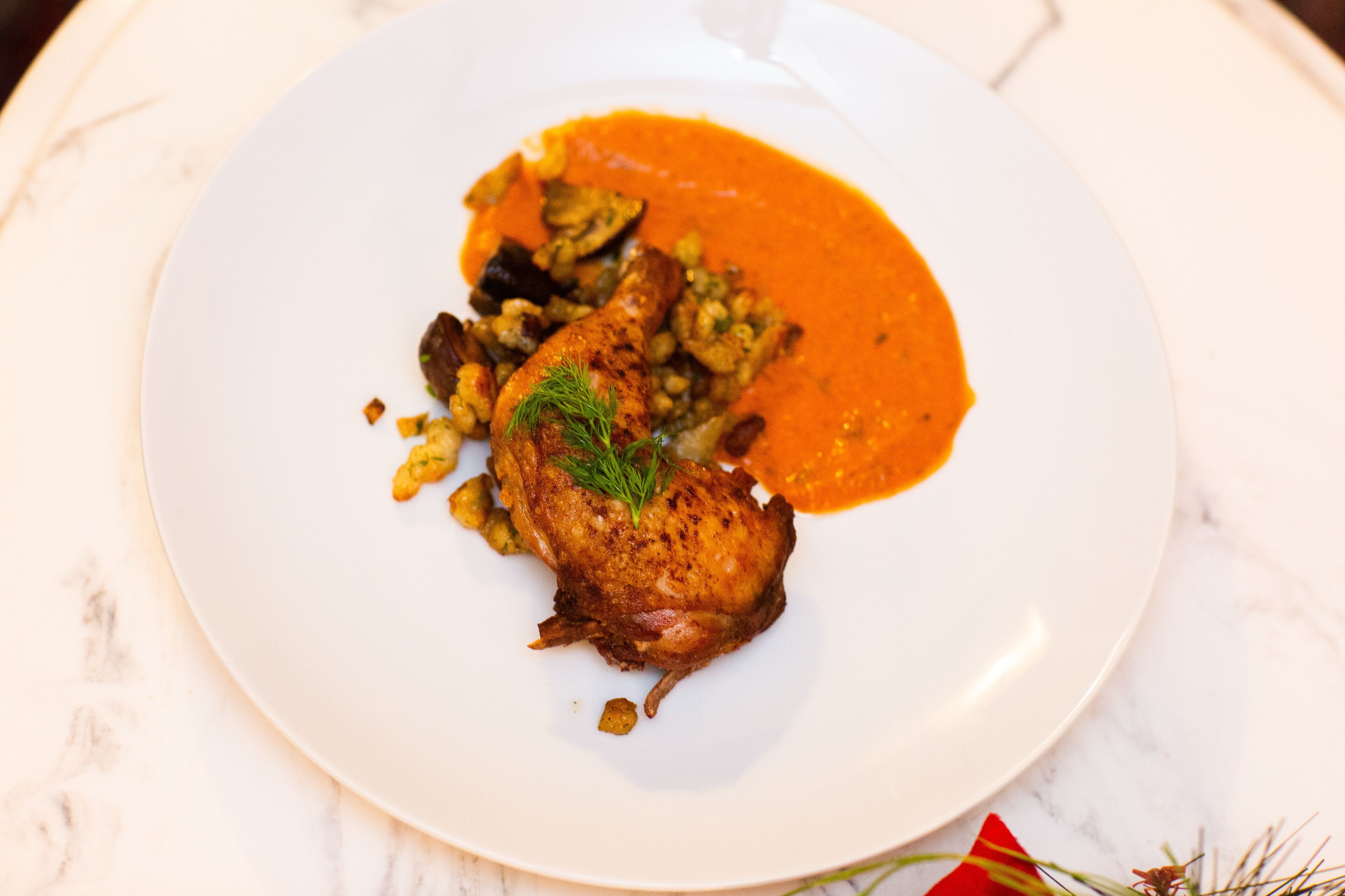 Um prato branco com uma sobrecoxa de frango assada, cogumelos e molho de tomate.