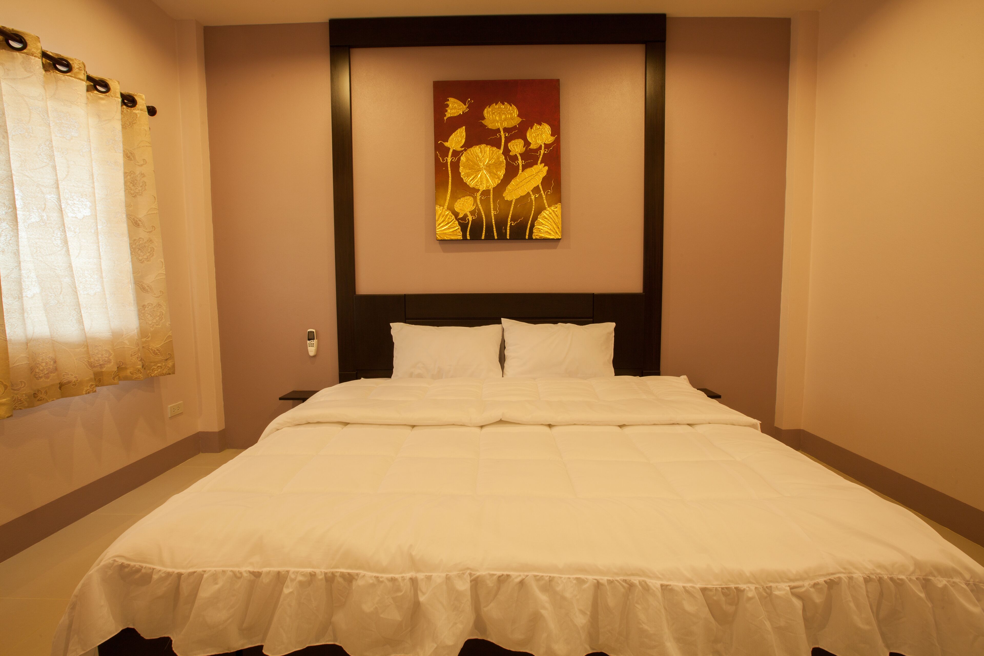 Cama bem arrumada com lençóis brancos, cabeceira e uma obra de arte na parede com flores amarelas.