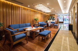 Um lobby moderno com painéis de madeira, assentos azuis e piso de mármore.