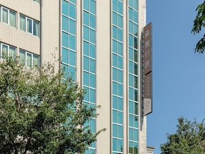 Um edifício de vários andares com uma grande placa vertical indicando um hotel.