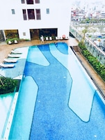 Piscina no terraço com várias pistas, rodeada por espreguiçadeiras e plantas em vasos.