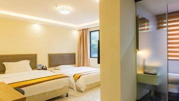 Quarto de hotel com duas camas, uma escrivaninha de madeira, um separador de vidro e vista para o exterior.
