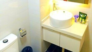 Um banheiro com pia branca, espelho acima e vaso sanitário.