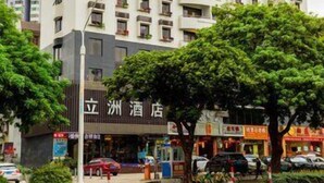 Um hotel com vários andares, varandas e área comercial no térreo com lojas.