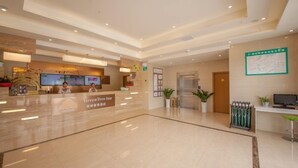 Uma área de recepção de hotel com design moderno, um balcão de recepção, uma tela digital e um mapa na parede.