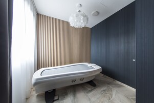 Um spa moderno com uma mesa de massagem, ripas de madeira e uma parede escura.