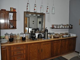 Cozinha com armários de madeira, cafeteira, chaleira e diversos utensílios de cozinha.