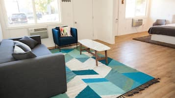Uma sala de estar moderna com um sofá cinzento, uma poltrona azul e uma mesa de centro branca.