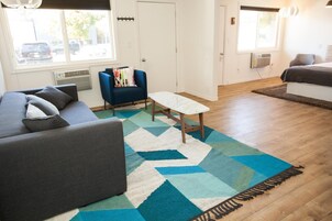 Uma sala de estar moderna com um sofá cinzento, uma poltrona azul e uma mesa de centro branca.