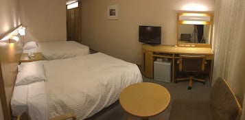 Quarto de hotel com duas camas, uma escrivaninha com televisão, uma cadeira e uma pequena mesa.