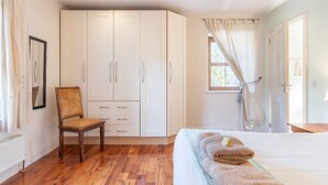 Quarto com cama, cadeira, guarda-roupa e janela com cortinas.