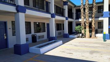 Um hotel de vários andares com um pátio central, com varandas e palmeiras.