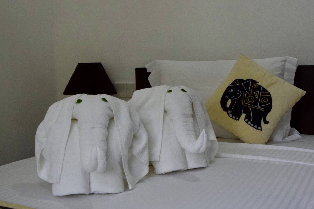 Uma cama com duas toalhas em formato de elefante branco e um travesseiro com desenho de elefante.