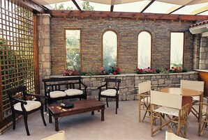 Um pátio externo com paredes de pedra, móveis de madeira e caixas de flores.