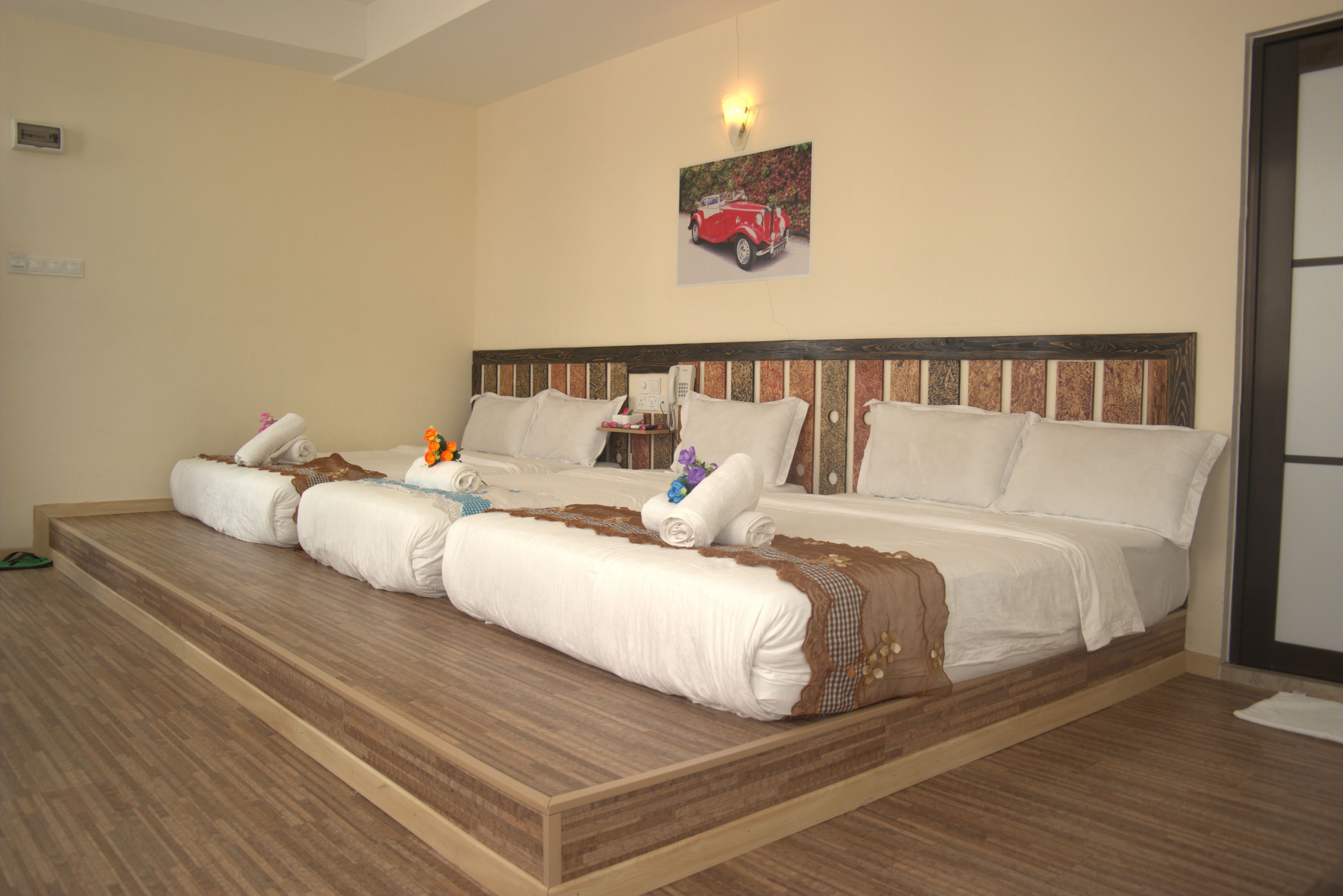 Uma cama grande com estrutura de madeira e cabeceira estampada em listras. Há várias almofadas e um cobertor sobre a cama.
