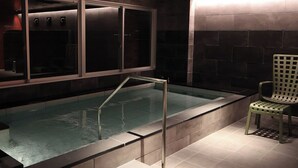 Piscina com barreira de vidro e uma cadeira.