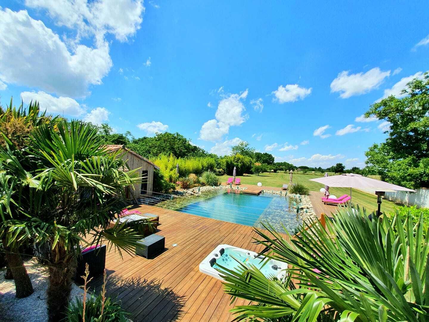 Um deck de madeira com piscina, cadeiras de descanso e ofurô.