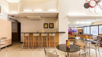 Uma cozinha moderna com área de bar, banquetas e uma mesa de jantar com cadeiras.