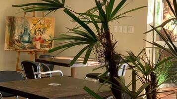 Uma sala de conferências com um quadro na parede, uma mesa, cadeiras e um vaso de planta.