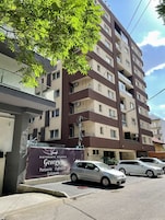 Um edifício residencial com vários andares, varandas e um banner publicando uma pizzaria.