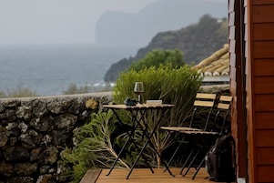 Um deck de madeira com mesa e cadeiras, com vista para a costa.