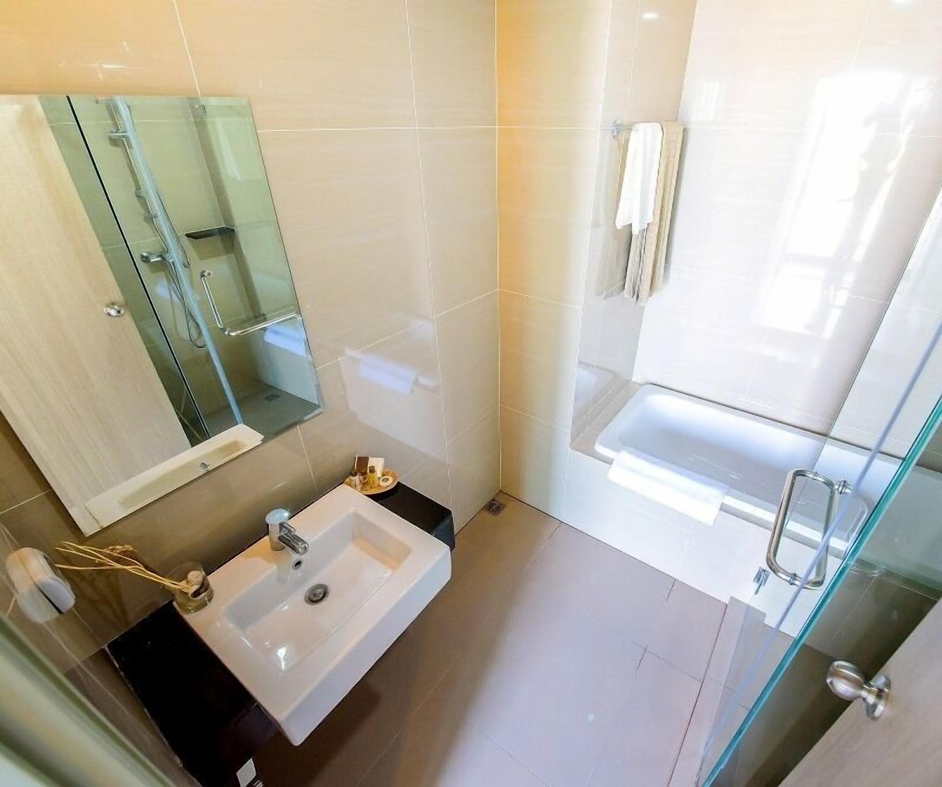 Uma casa de banho moderna com cabine de duche em vidro, lavatório branco e espelho grande.