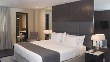 Quarto de hotel moderno com uma cama grande, uma escrivaninha e uma televisão.
